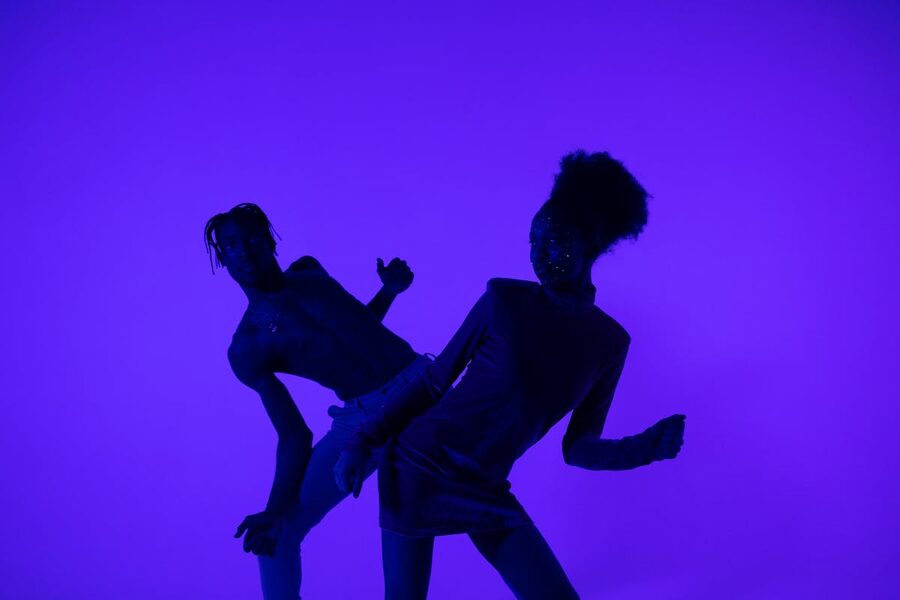 Dancers silhouetted under neon purple stage lights