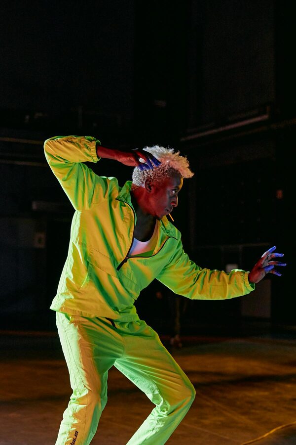 Dancer in neon green under dramatic stage lighting