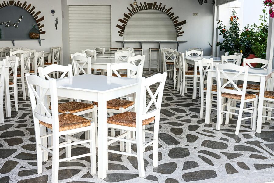 Traditional Greek cafe with outdoor seating and white chairs