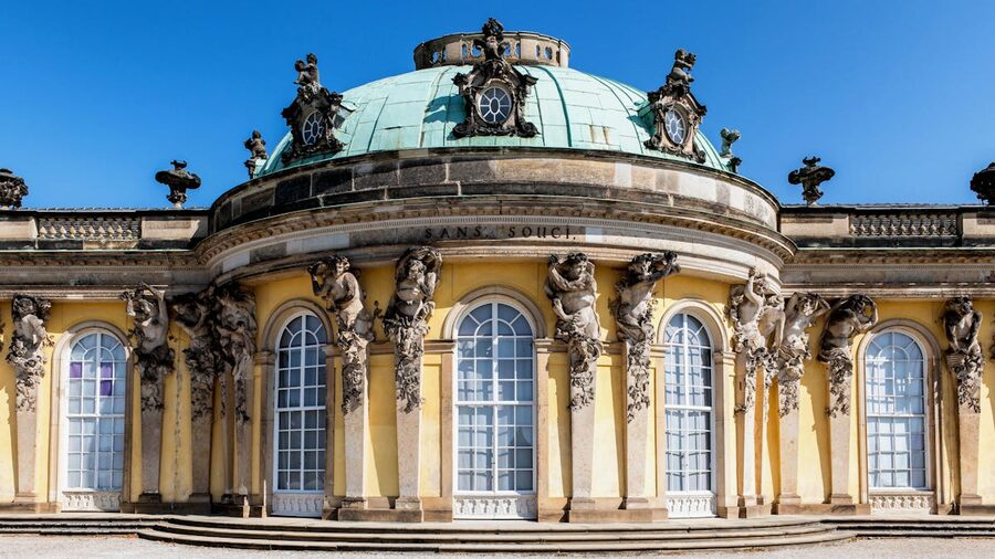 Ornate facade of Sanssouci Palace with gold leaf details and caryatid sculptures