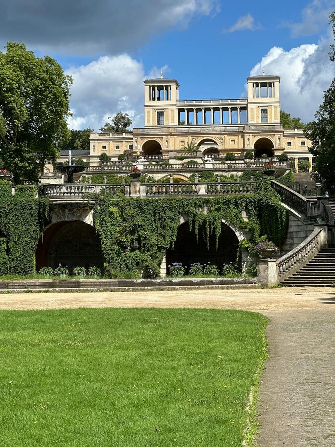 Terraced gardens at Sanssouci Palace under bright blue sky