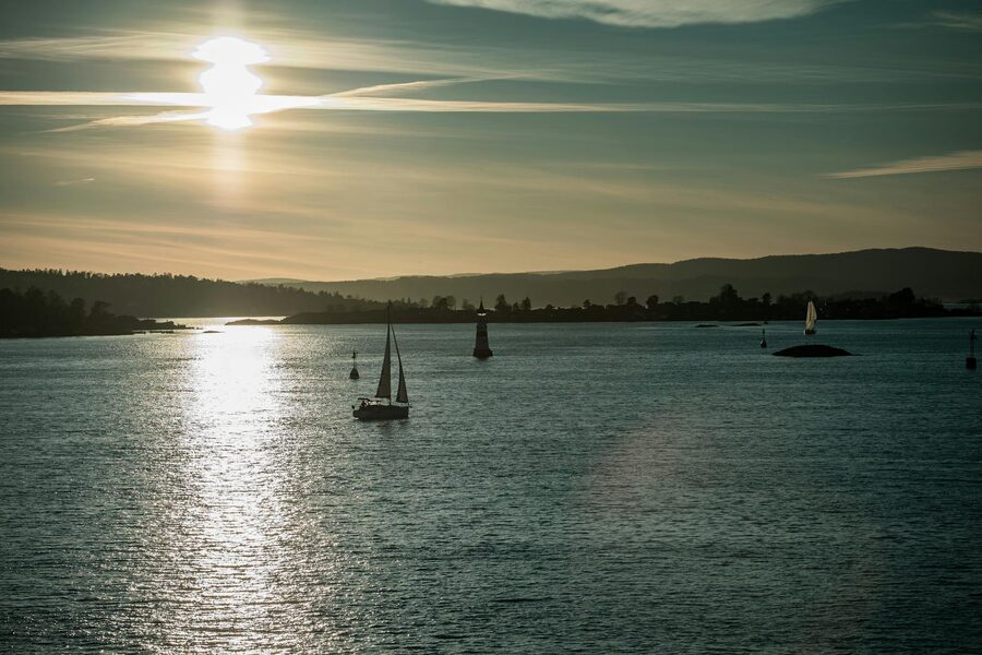 Sailboats on Oslo fjord at sunset with lighthouse