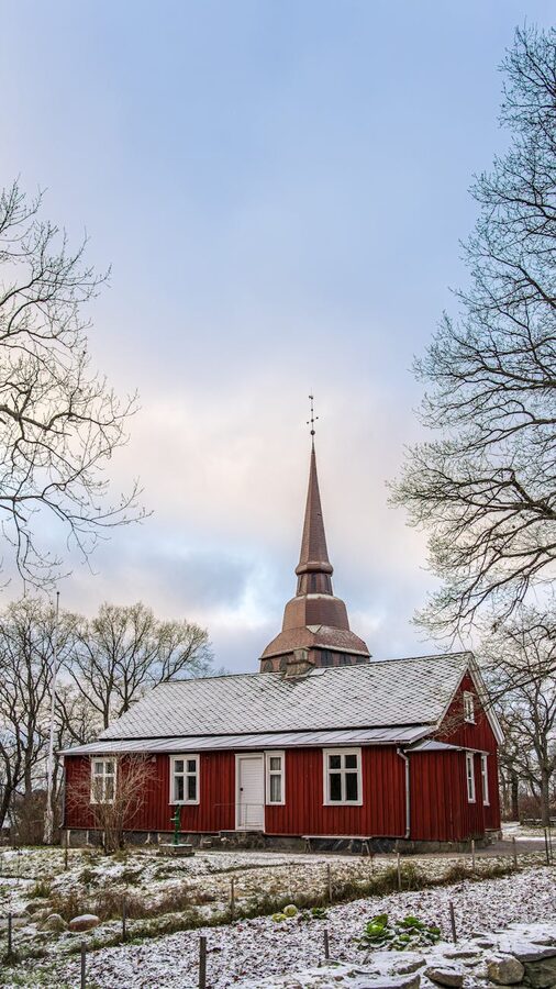 Red timber church with snow on roof at Skansen museum