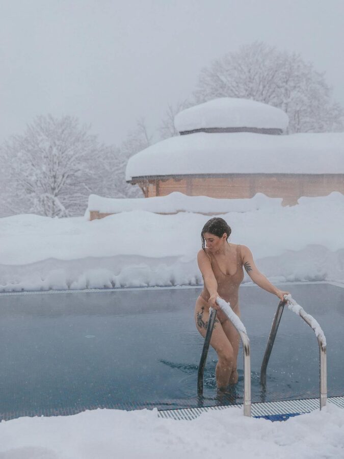Woman entering steaming outdoor pool in winter