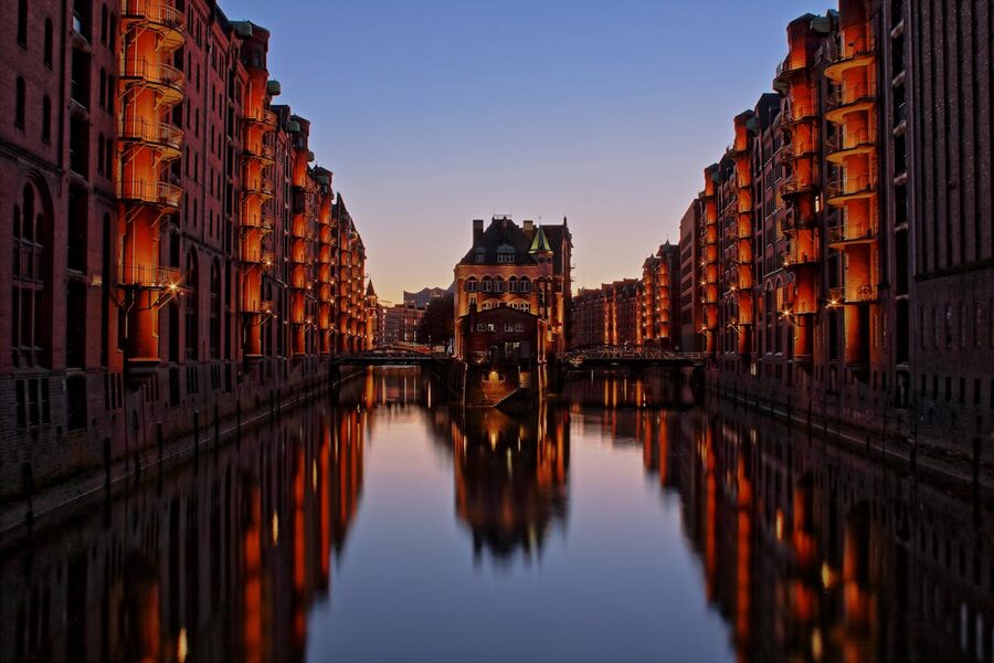 The Wasserschloss building at twilight in Hamburg's Speicherstadt, reflected in canal water