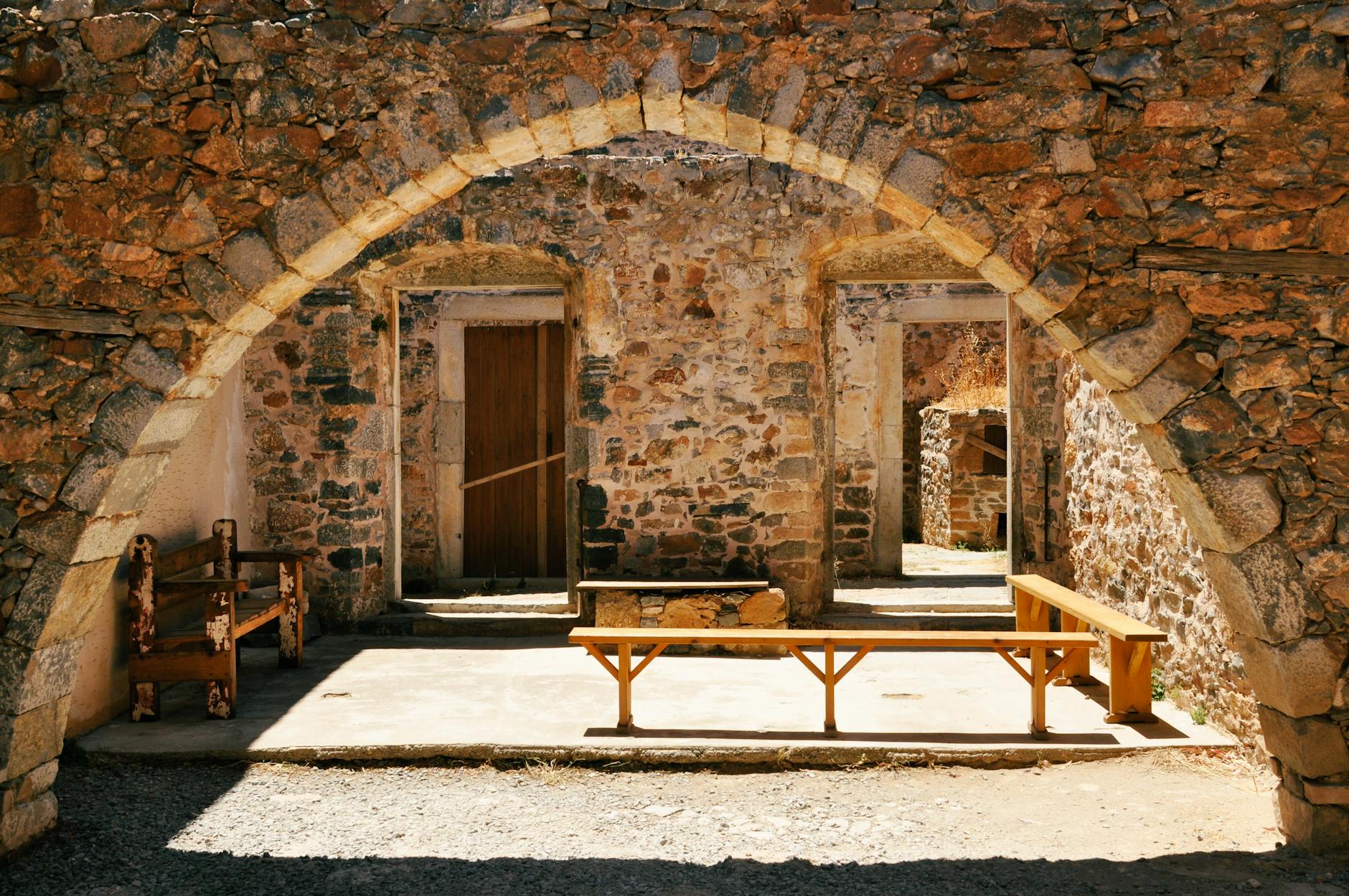 Sunlit courtyard with stone archway on Spinalonga