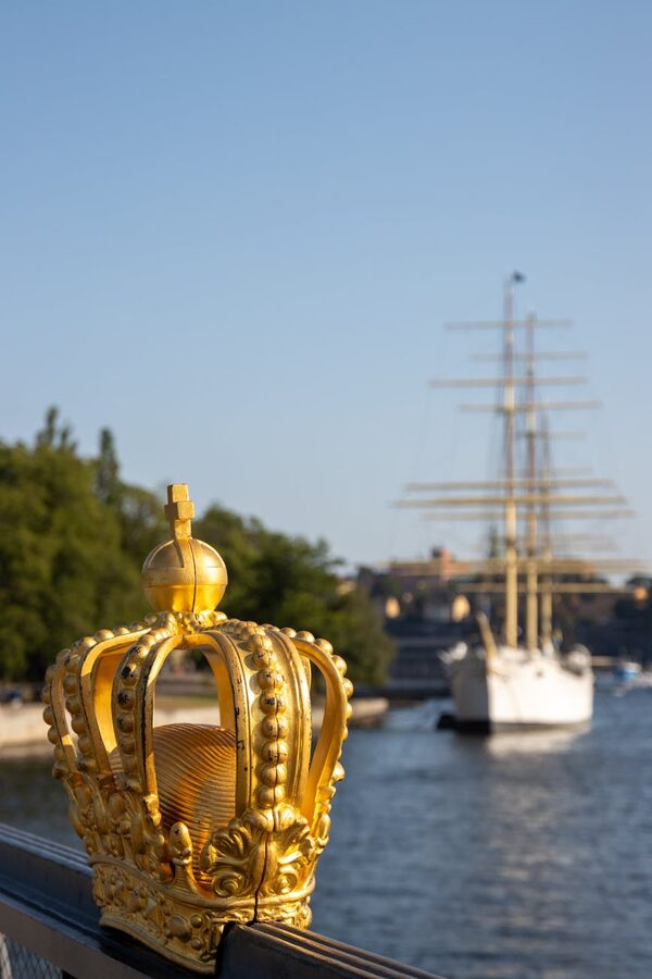 Golden crown sculpture with sailboat in Stockholm harbor