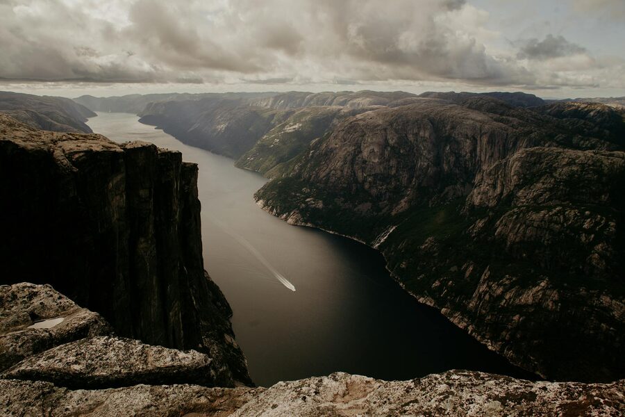 Aerial view of a boat in a narrow Norwegian fjord surrounded by cliffs