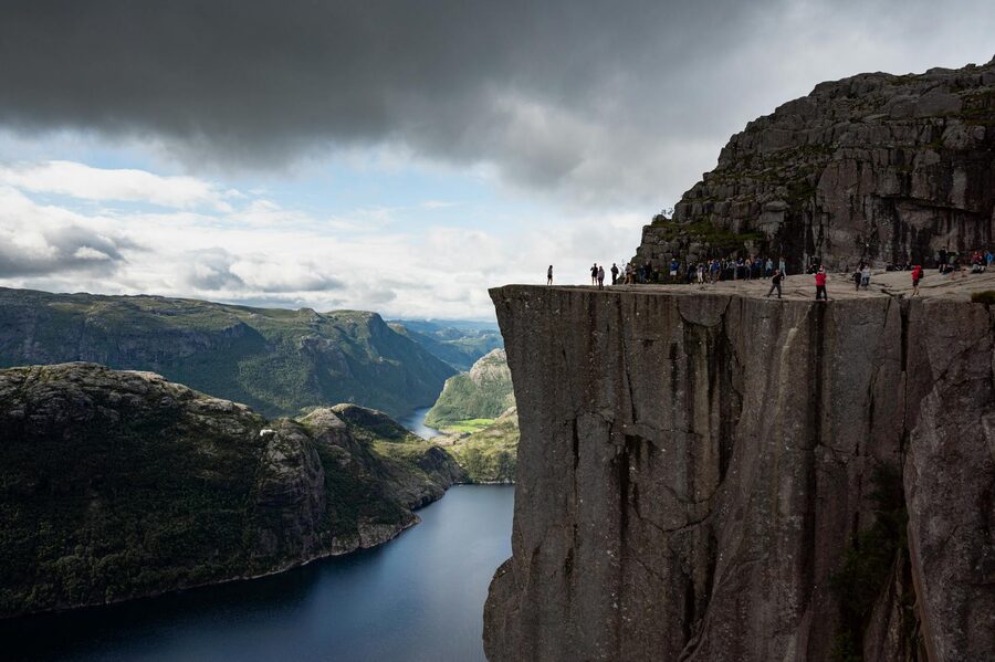 Hikers on Preikestolen cliff overlooking the Lysefjord far below