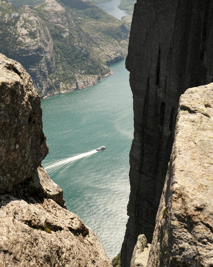 Motorboat cruising through a fjord with steep cliffs on a sunny day