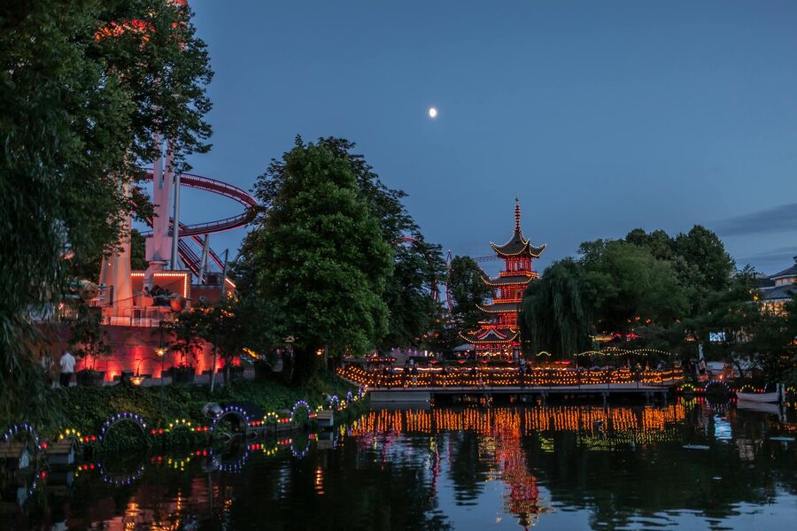 Tivoli Gardens pagoda at night with colorful lights reflected in lake