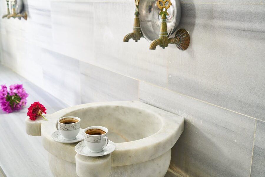 Turkish coffee cups on marble sink with ornate faucets
