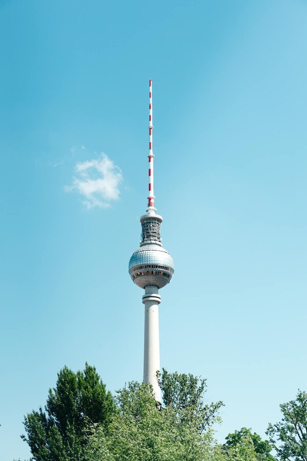 Berlin TV Tower against bright blue sky seen from street level