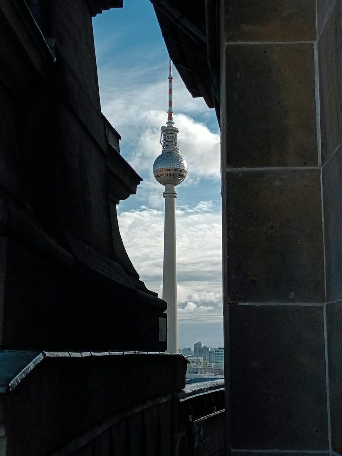 Berlin TV Tower framed between dark architectural structures creating dramatic composition