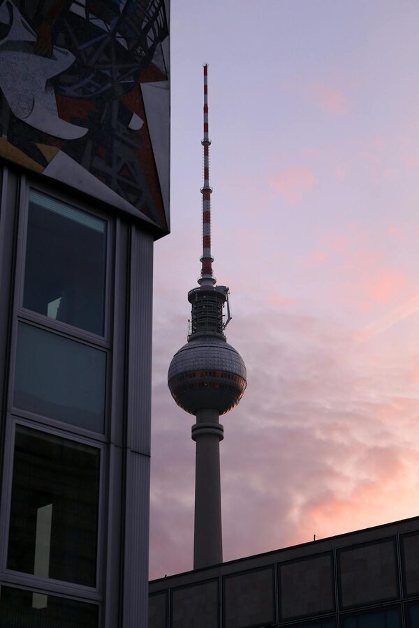 Berlin Fernsehturm TV Tower during sunset with urban foreground buildings