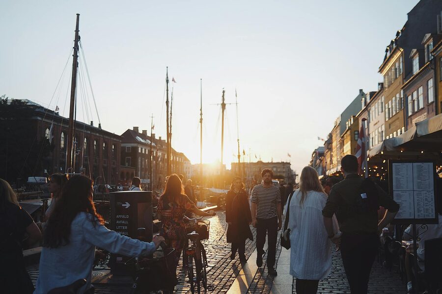 People strolling along Nyhavn canal at sunset in Copenhagen