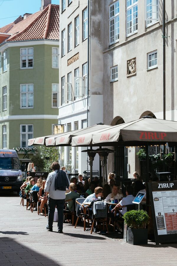 People dining at an outdoor cafe on a Copenhagen cobblestone street