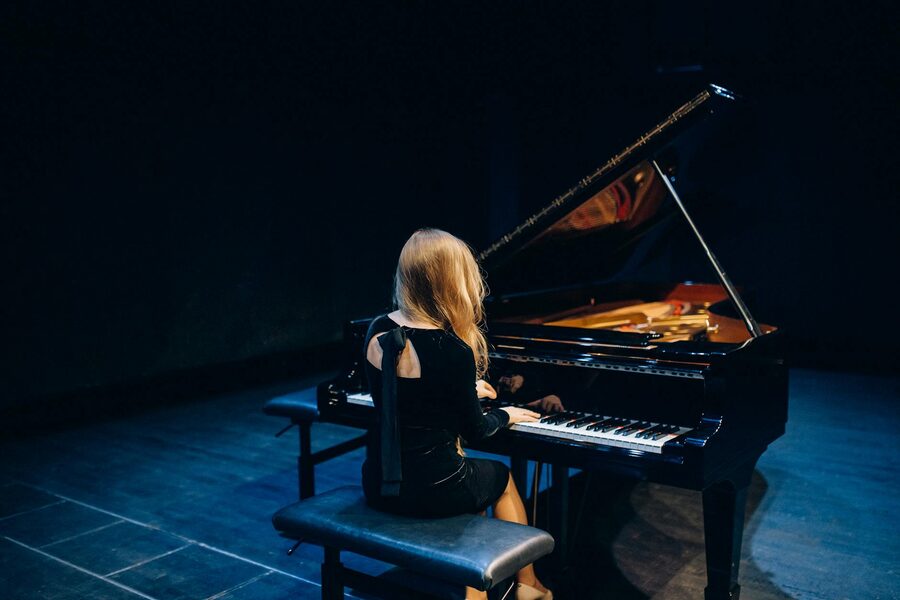 Female pianist performing on grand piano on stage