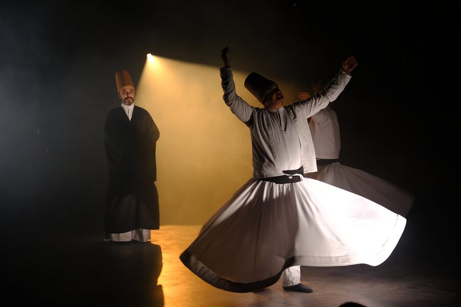 Whirling dervishes performing under dramatic stage lighting