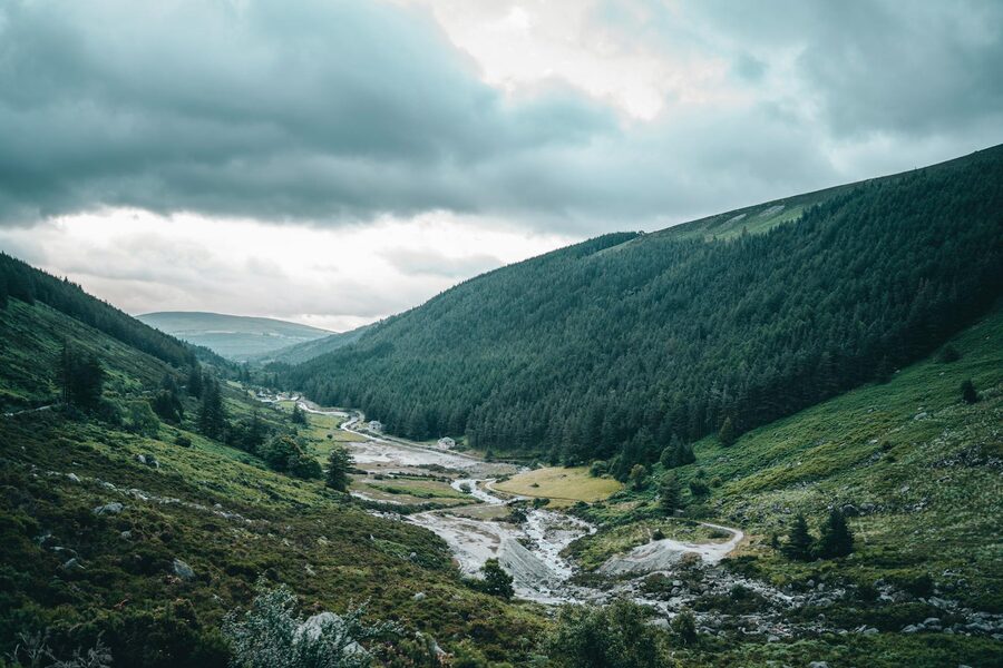 Green valley with river flowing through Wicklow Ireland under cloudy skies