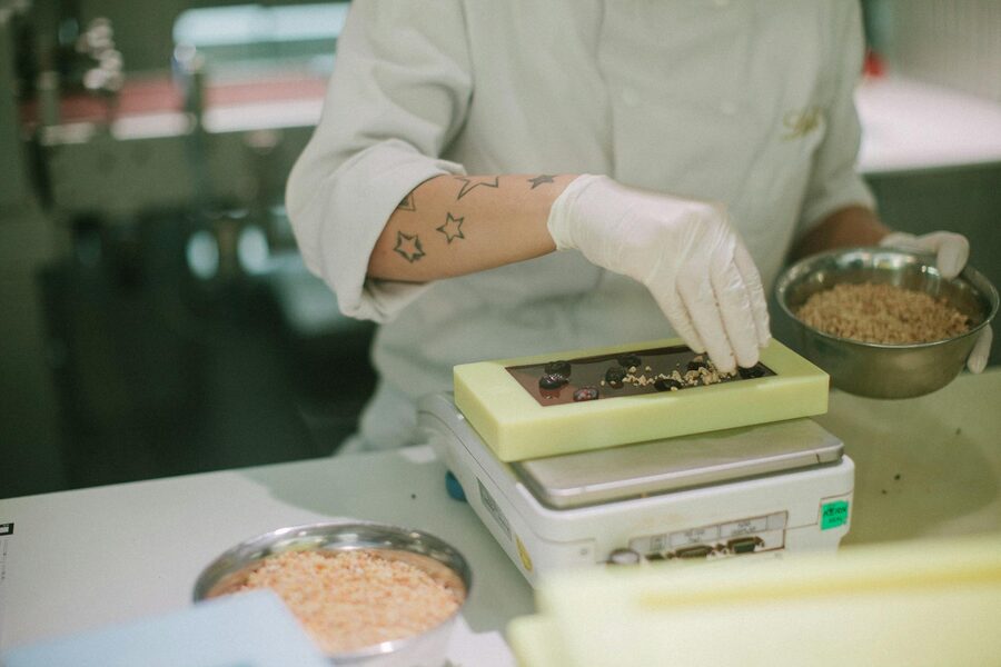 Chocolatier workspace with rows of topping ingredients and tools for handmaking chocolates