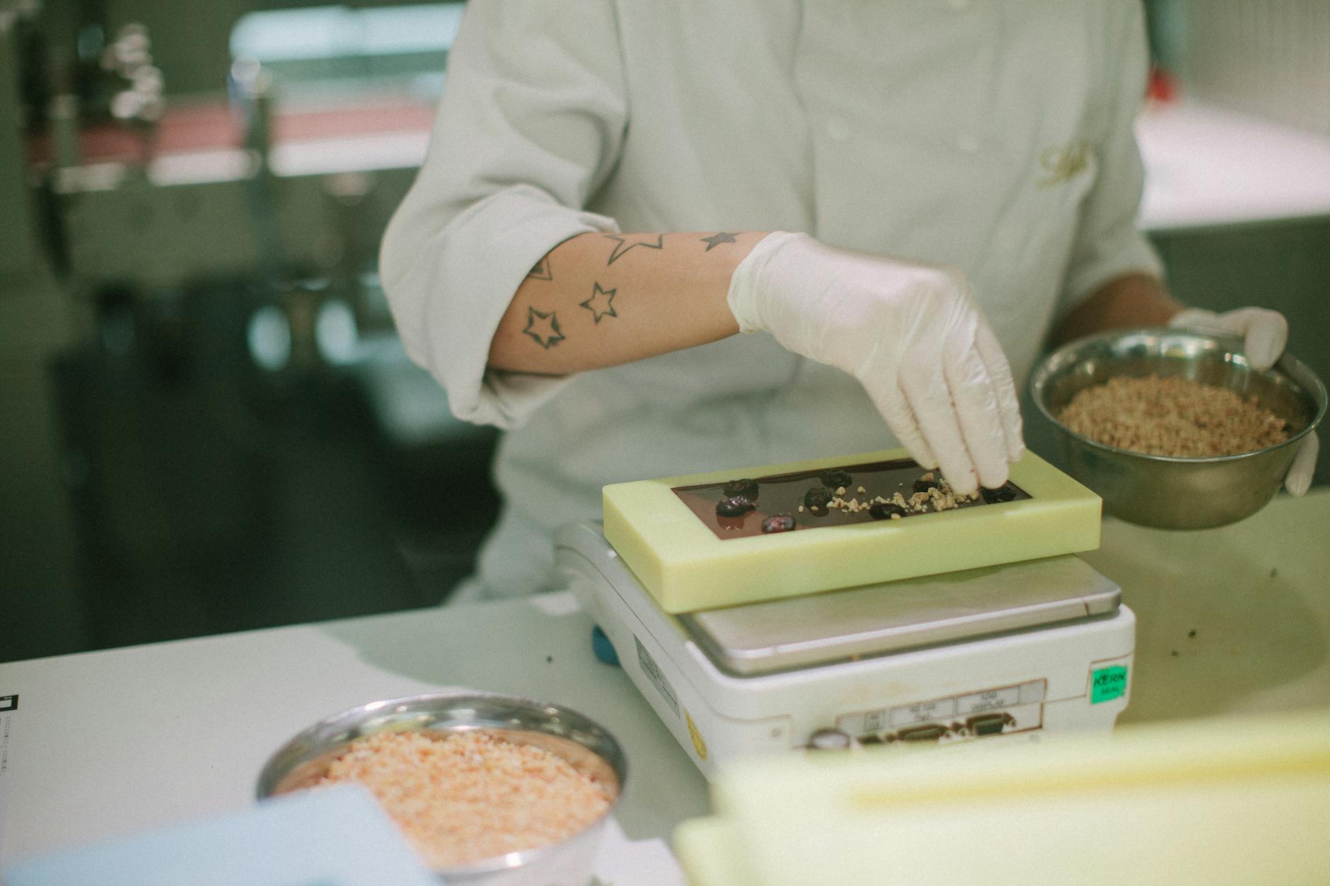 Chocolatier adding toppings to a chocolate bar